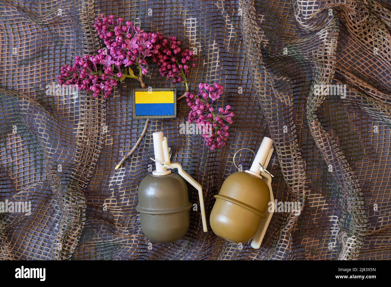 A military hand grenade lies on a camouflage net and next to the flag ...
