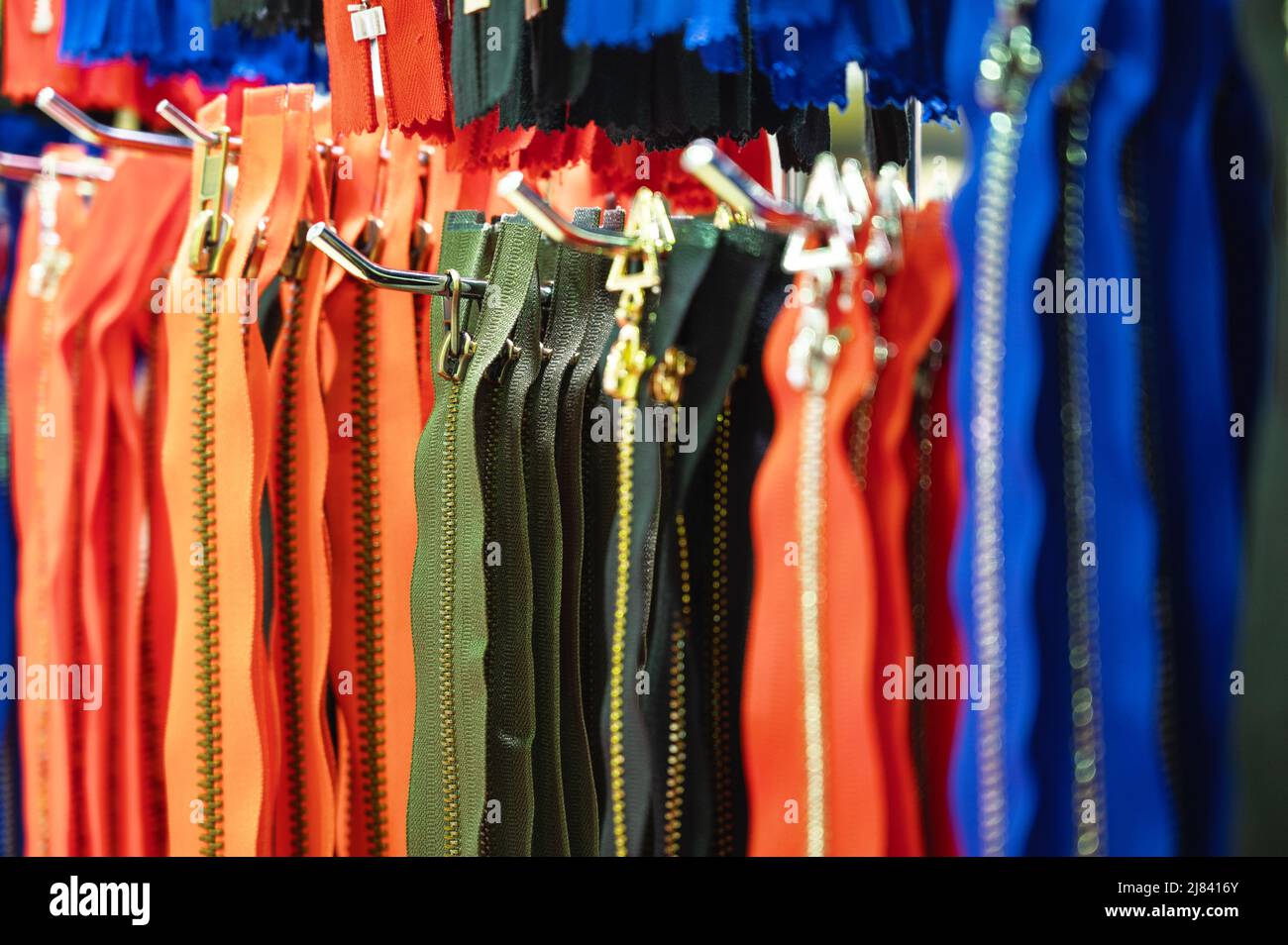 Group of zippers hangs on rack with hooks at exhibition Stock Photo - Alamy