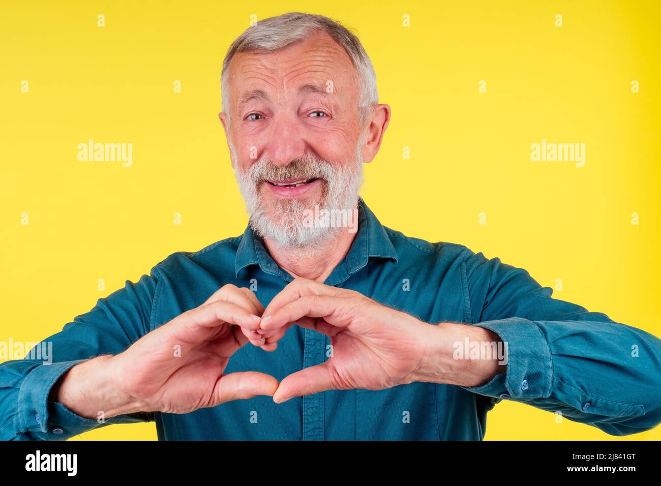 Happy senior man showing hand heart gesture and smiling, take care of ...