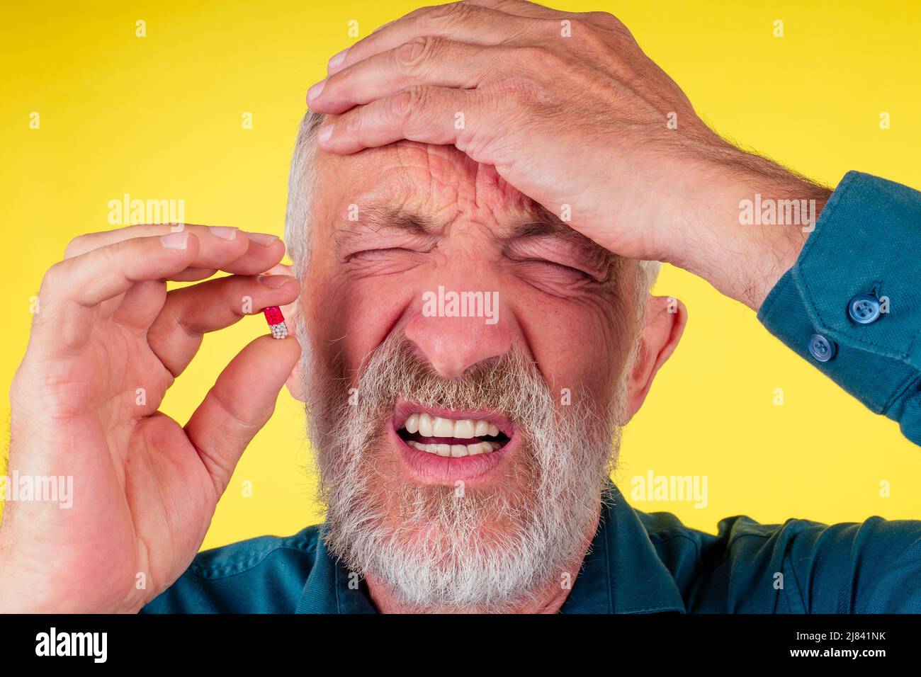 Senior older man holding a pain relief tablet or pill memory loss ...