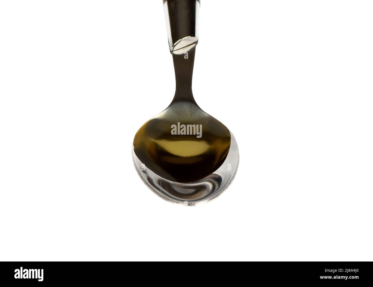 Metal spoon with a drop of sunflower oil on a white background. Copy ...