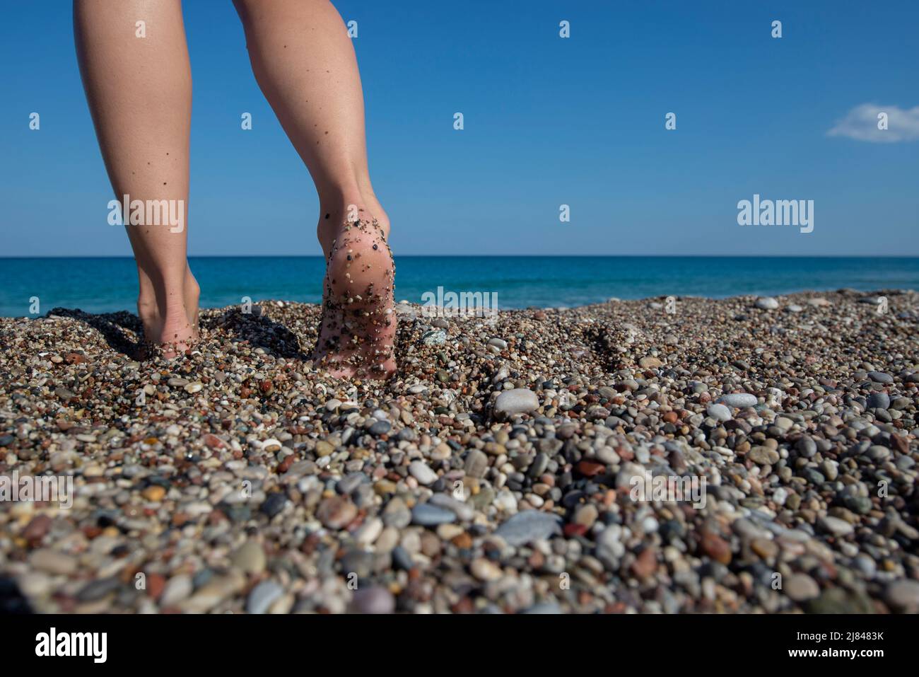 Low Angle View Of Female Feet Walking On A Beautiful Pebble Beach By
