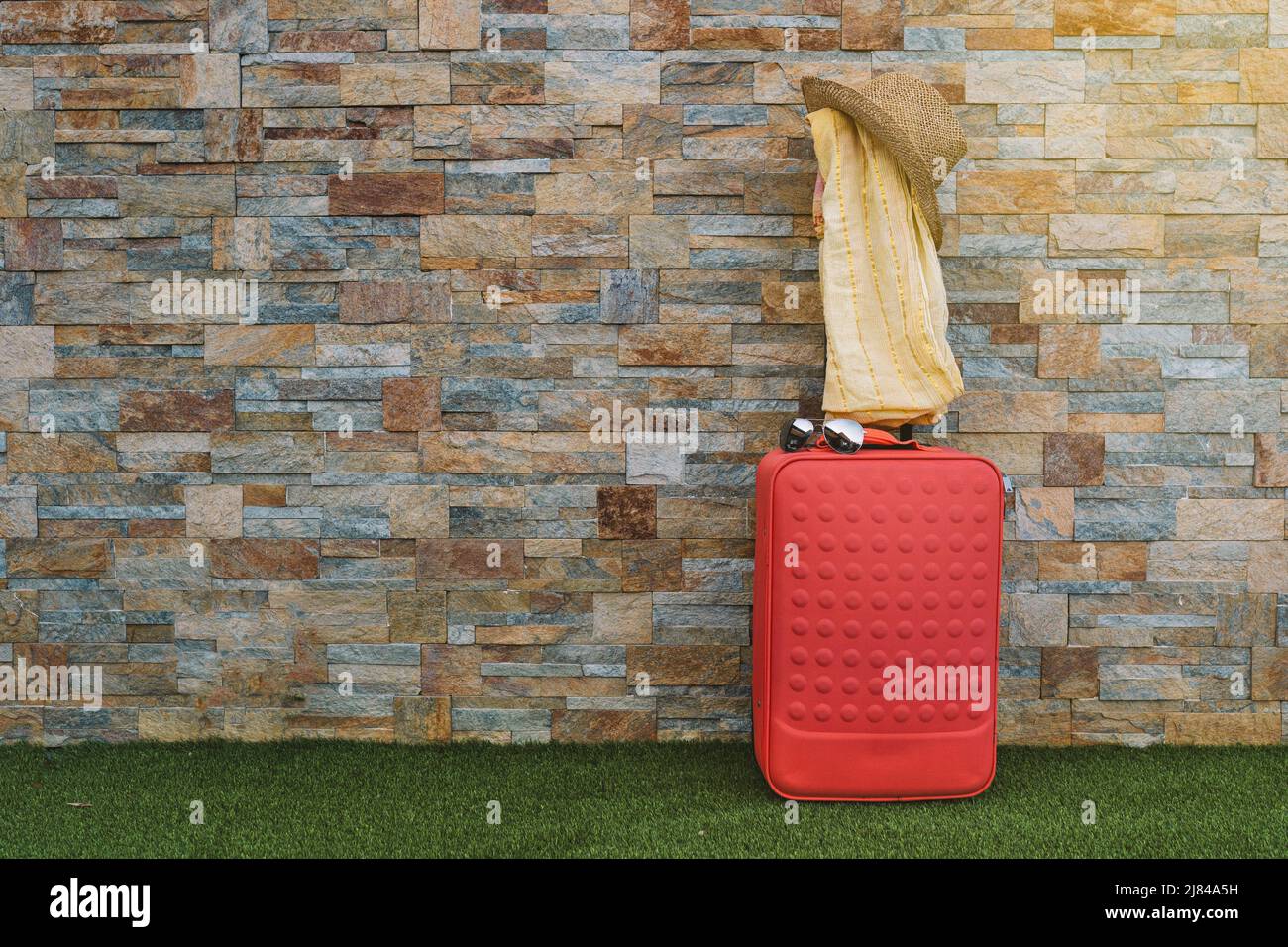 luggage in front of a stone wall and grass floor to use text. suitcase ...