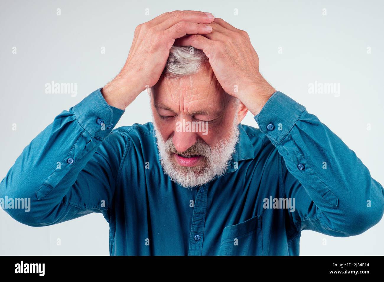 Elderly man with hand on his temple has a headache in studio white ...