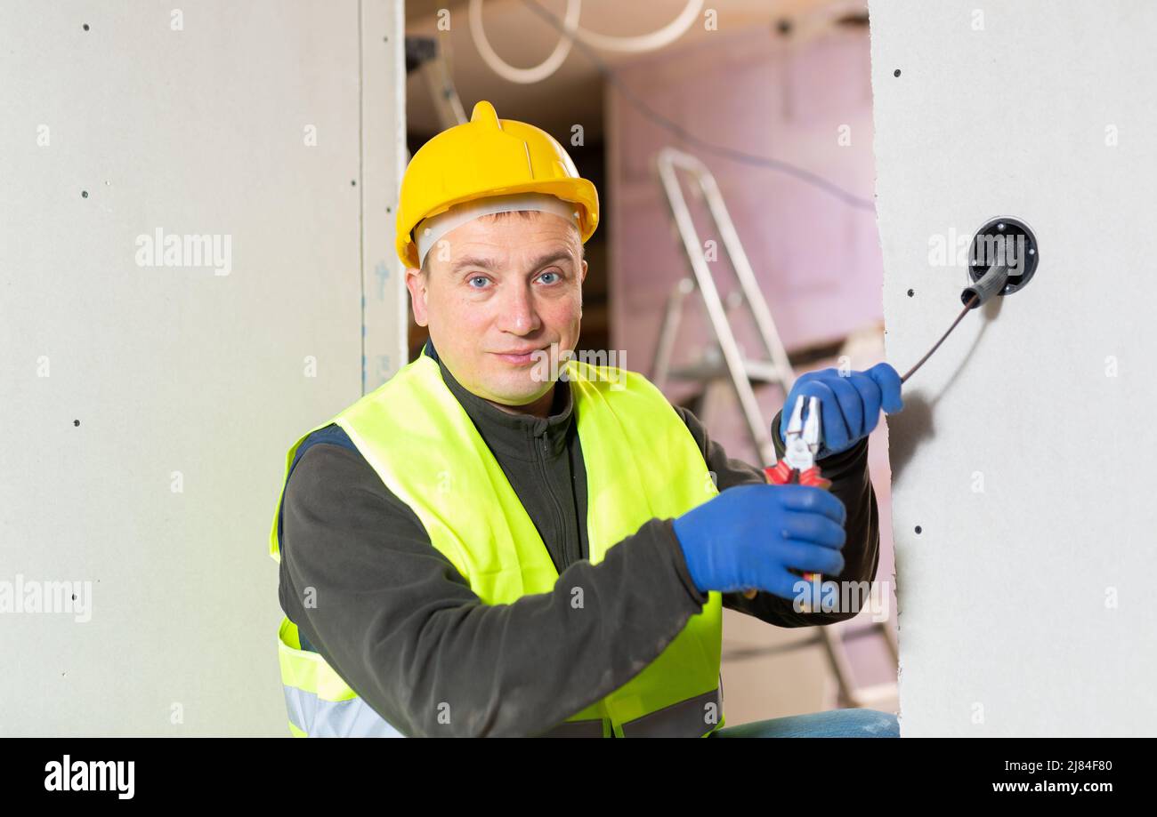 Electrician mounting electrical wiring inside building in process of ...