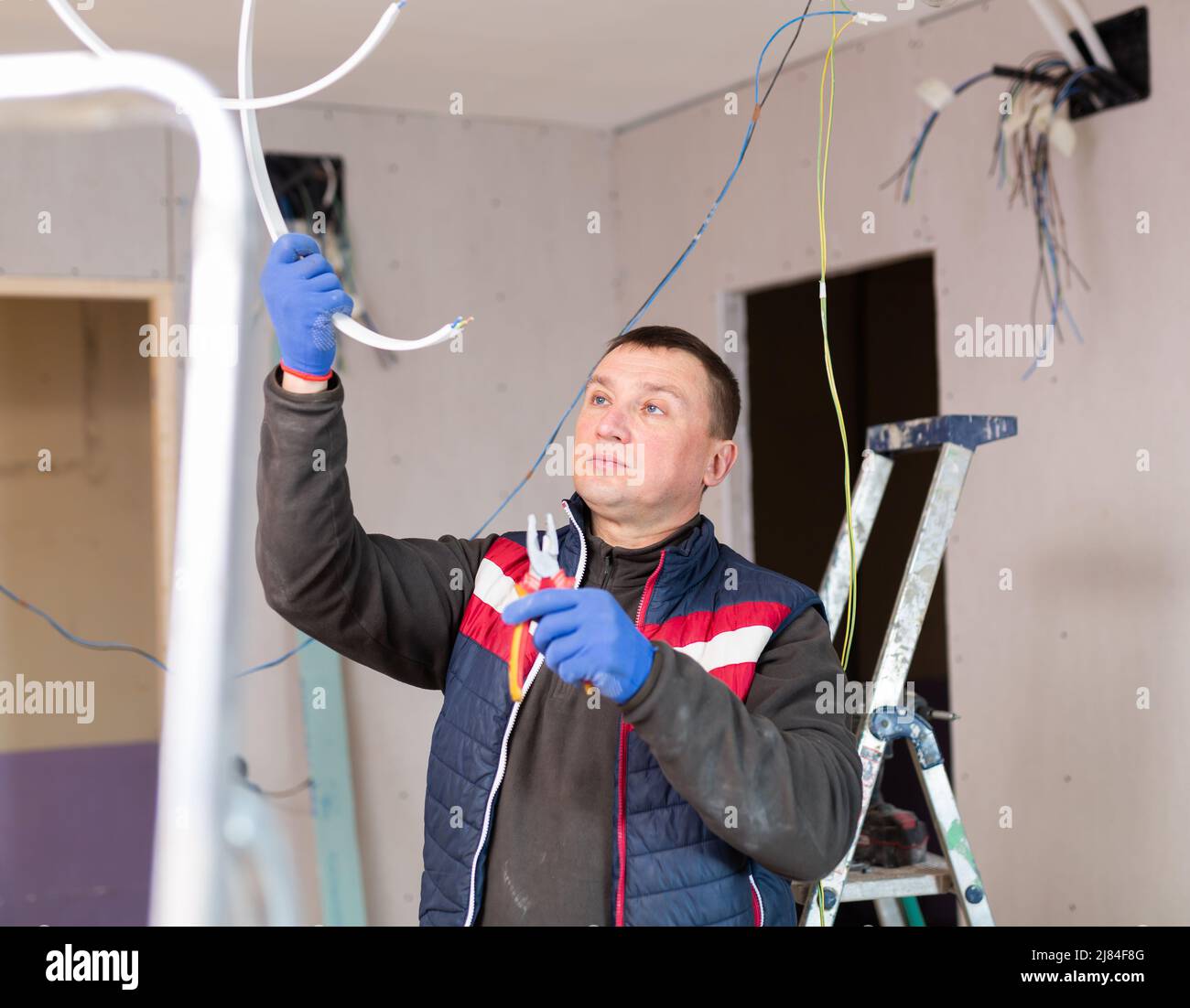 Experienced friendly electrician laying electric wires in building ...