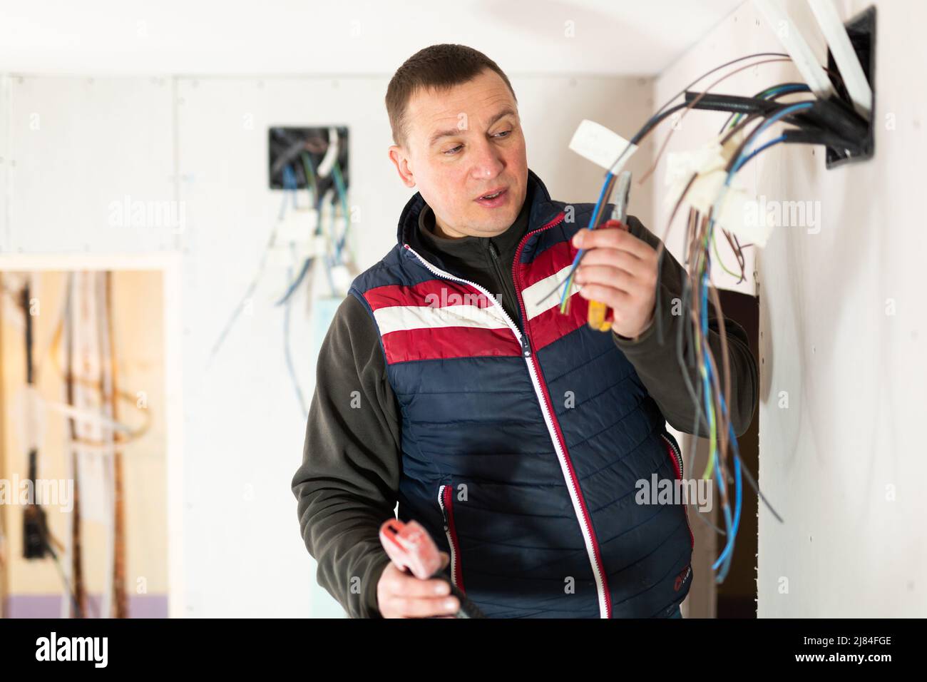 Professional builder engaged in electrical installation work at indoors ...