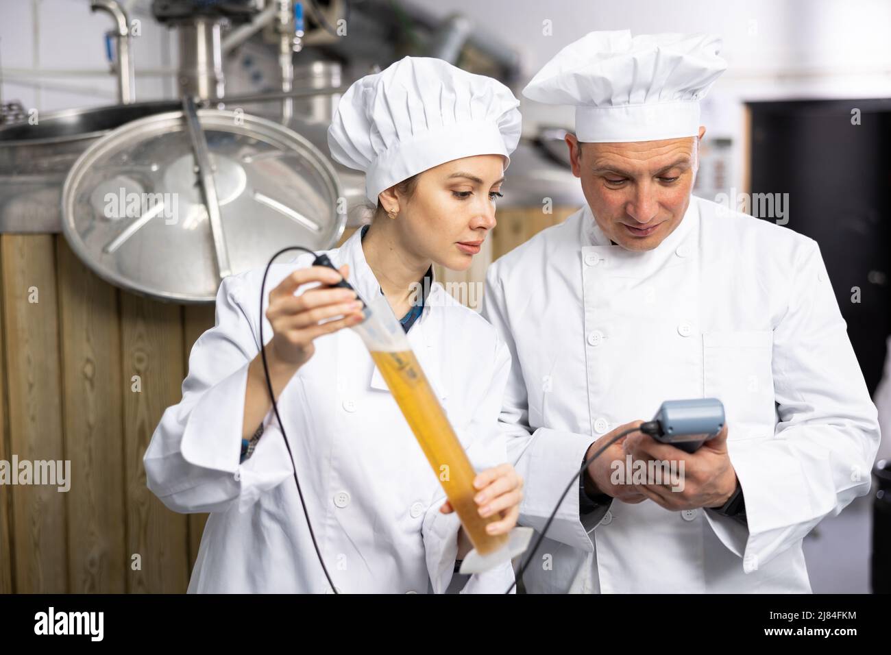 Man and woman brewmasters measuring beer with alcoholometer Stock Photo ...