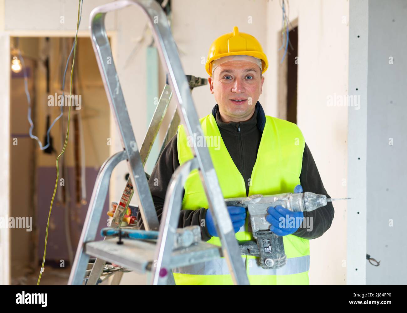 Repair man with drill standing in apartment Stock Photo - Alamy