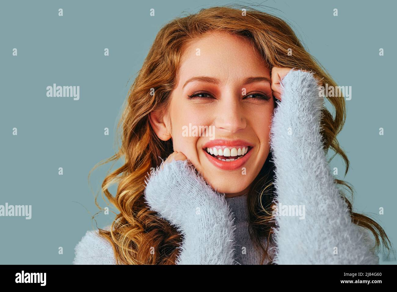 portrait of beautiful young smiling woman with long curly hair hands on ...