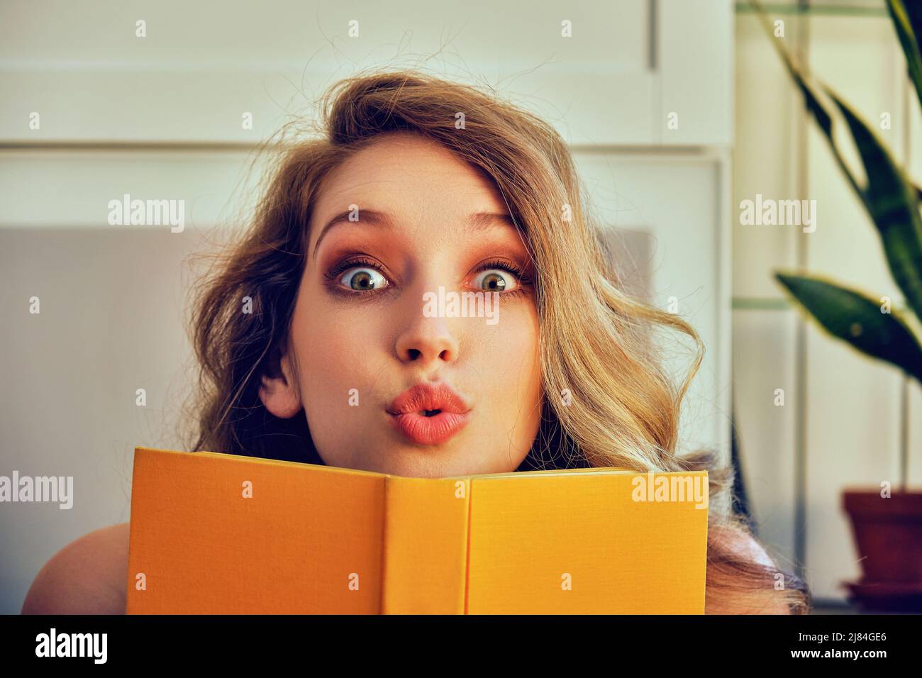 young woman with book looking at camera blowing kiss library Stock ...
