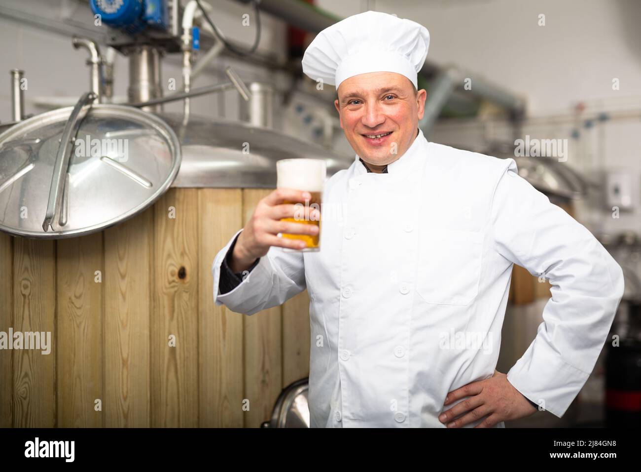 Successful brewmaster holding glass of foamy pale ale Stock Photo - Alamy