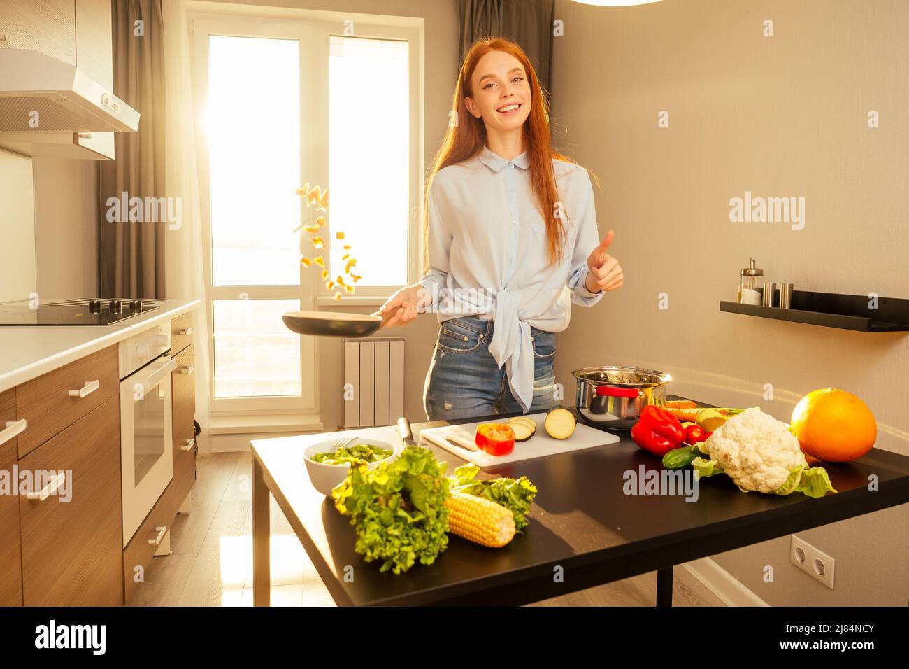 happy redhaired ginger woman cooking in evening sun lights sunset ...