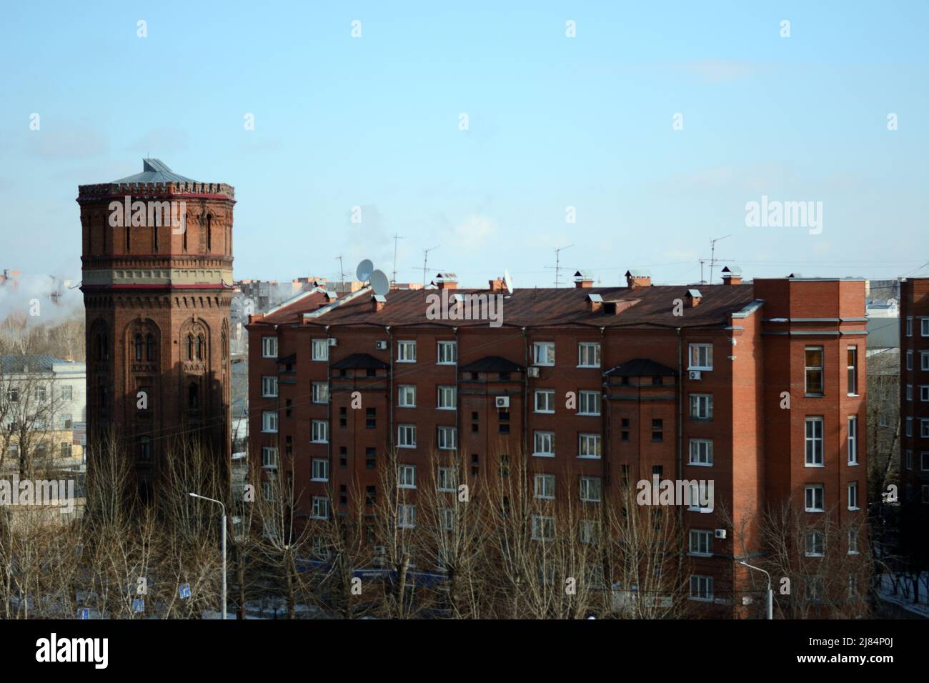 A brick tenement house and a tall old red brick fire tower in a dense ...