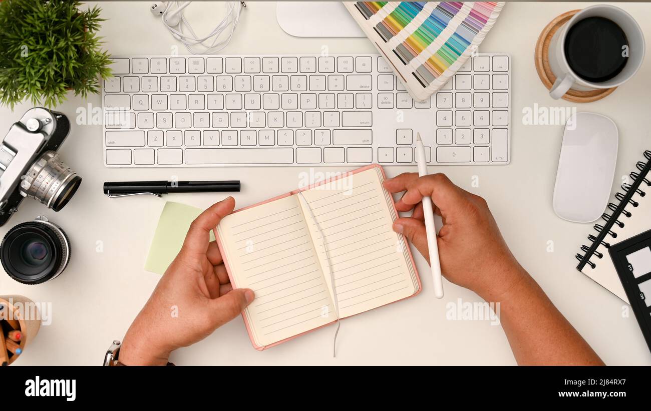 Male graphic designer taking notes on his personal notebook at his ...