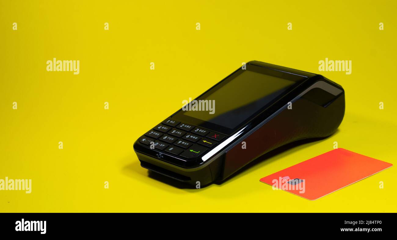 A Bank terminal incluiding a bank card on a yellow background with ...