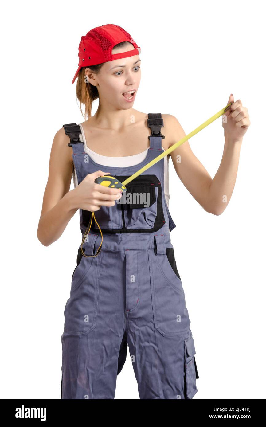 Young girl in overalls looking at building a tape measure in hand ...