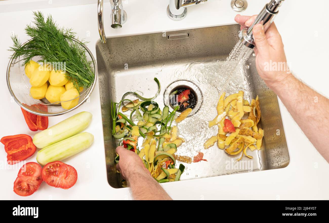 A man recycles food waste using a modern kitchen disposer Stock Photo ...