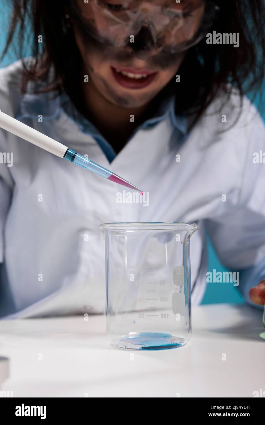 Close up of lunatic silly looking maniac biochemist using dropper to ...