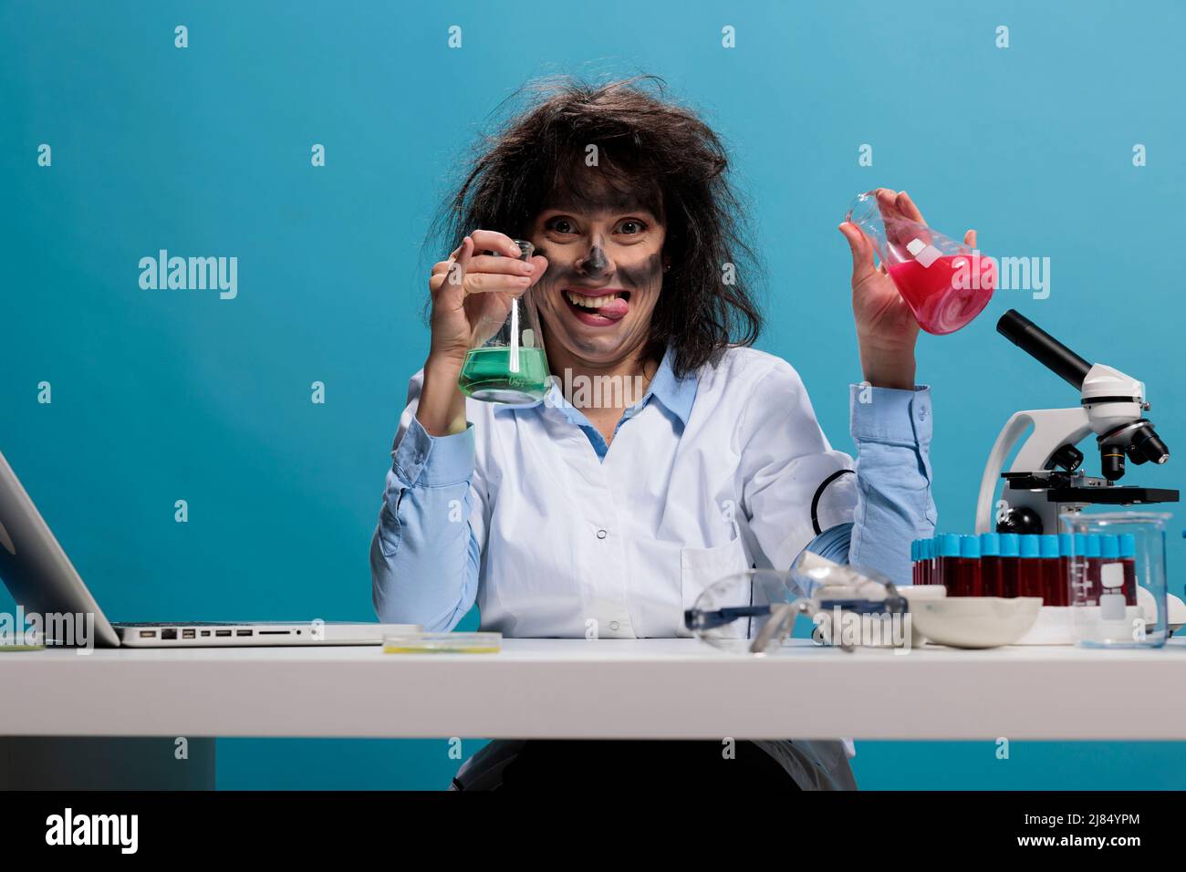 Foolish scientist with funny face expression handling beakers filled ...