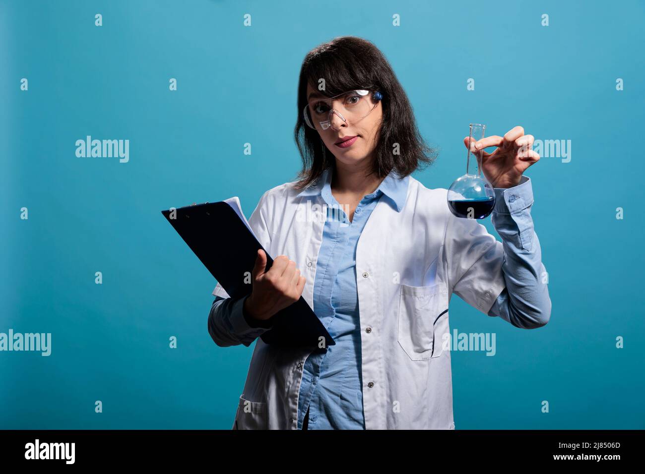 Biochemistry research specialist holding volumetric glass flask filled ...
