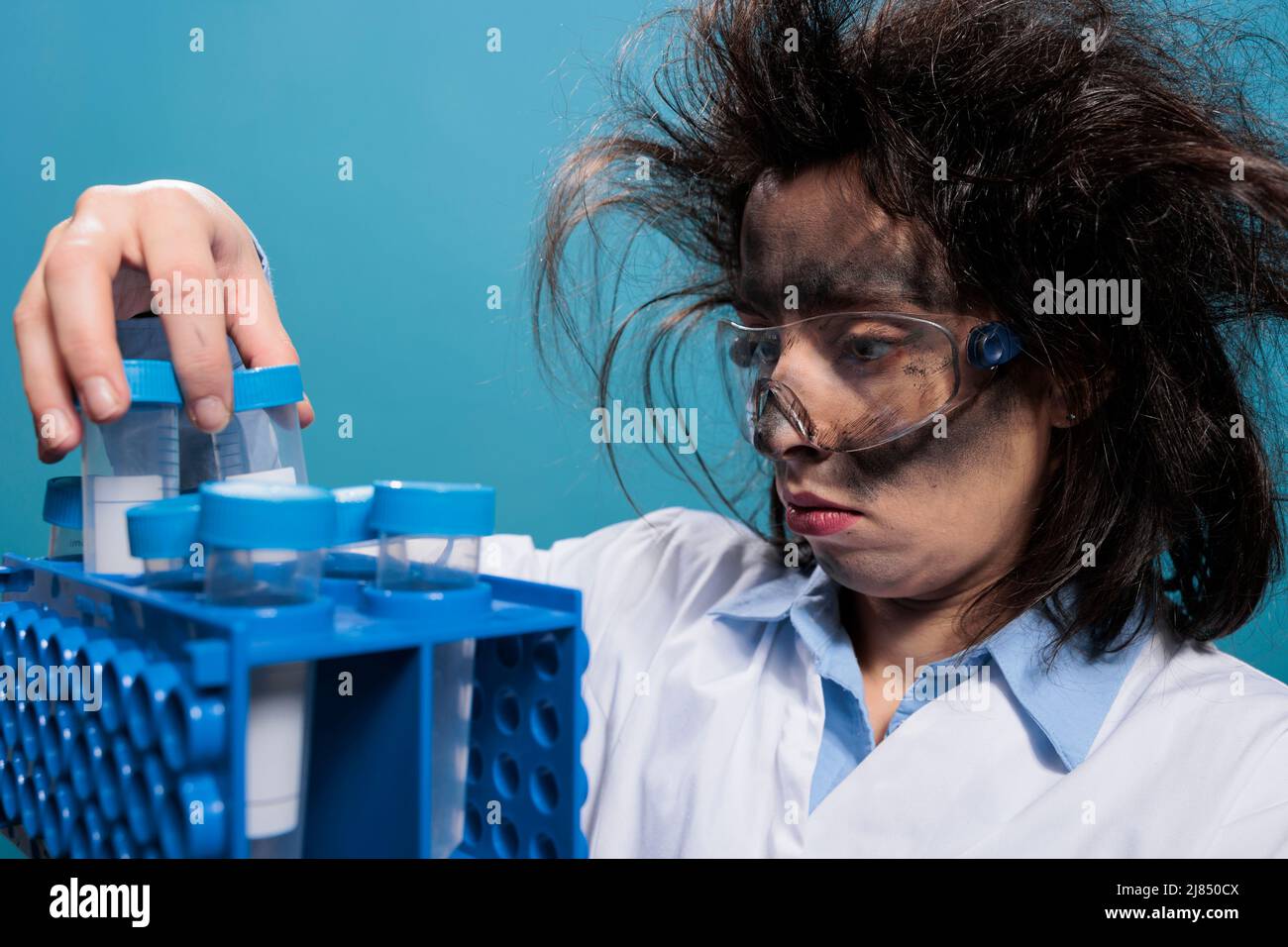 Crazy scientist with dirty face and messy hair analyzing plastic test ...