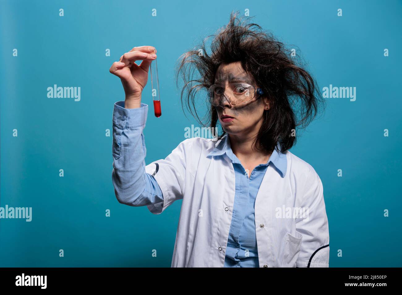 Insane anxious looking scientist analyzing chemistry glass tube filled ...
