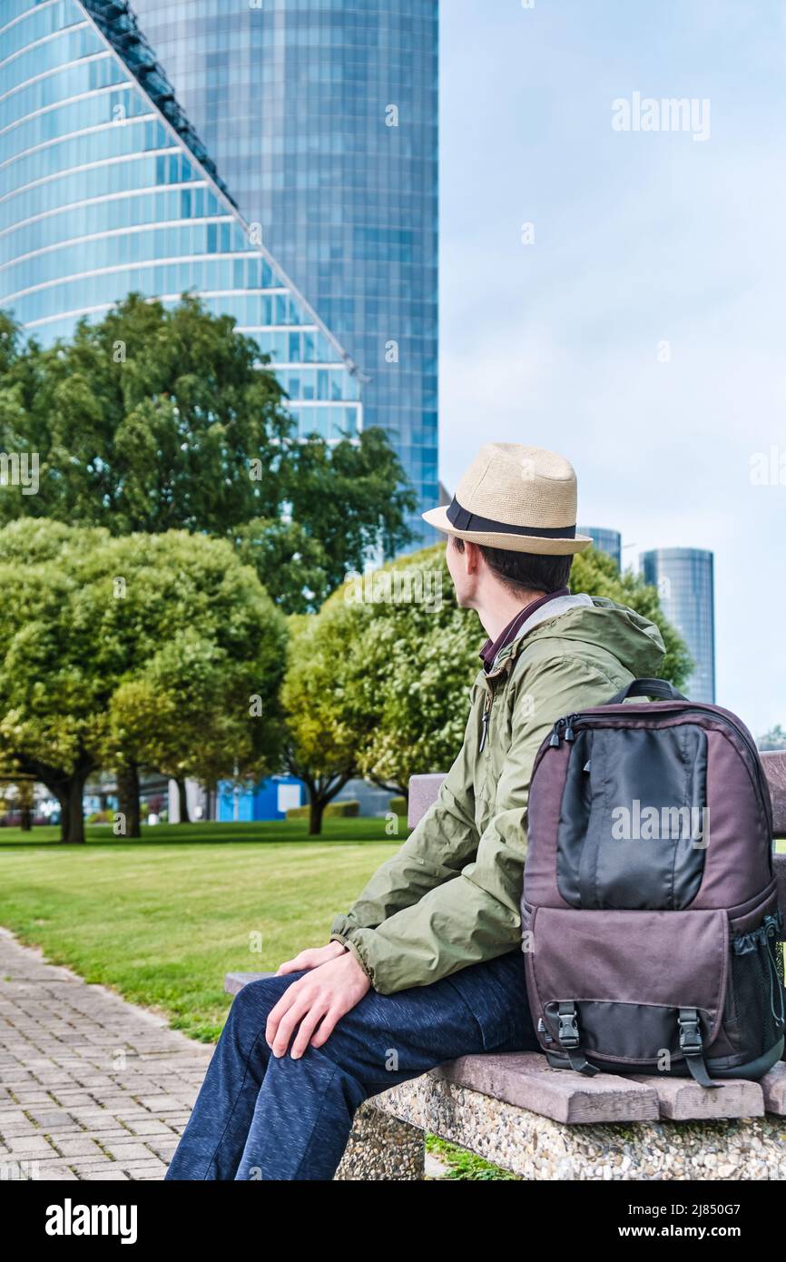 Young man seat and looks at the office building and thinks about work ...