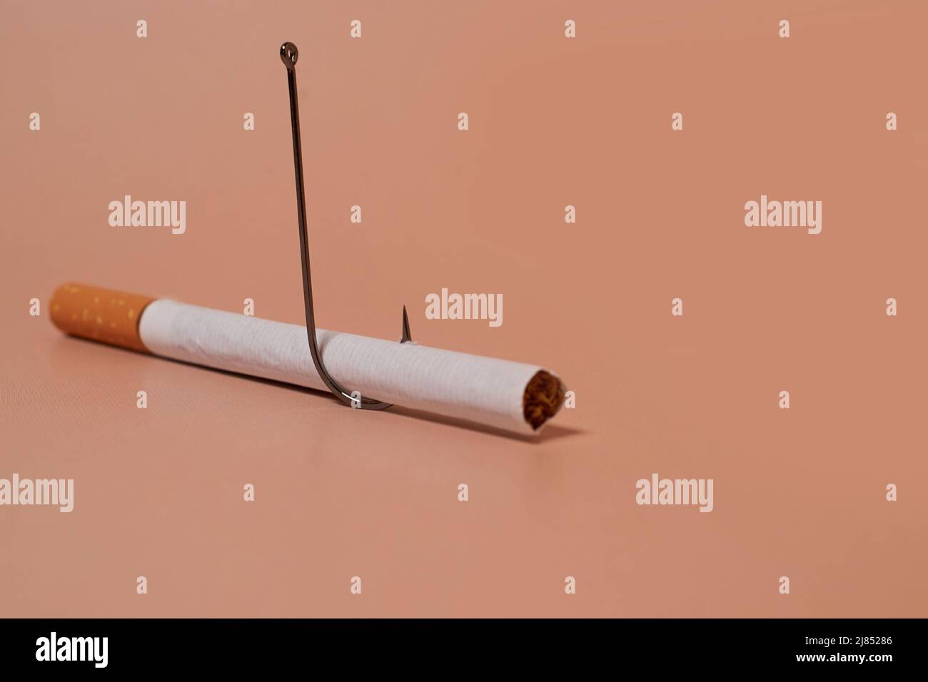 Cigarette with a fish hook on a colored background Stock Photo - Alamy