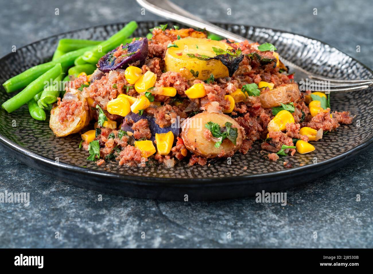 Corned beef, sweetcorn and potato hash with green beans Stock Photo - Alamy