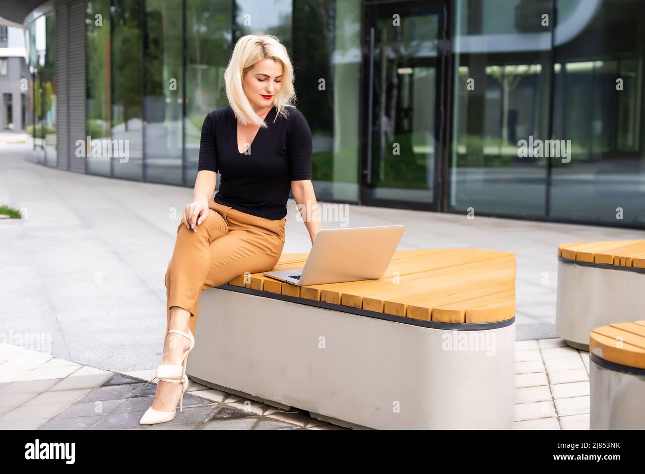 Young woman wearing smartwatch using laptop computer. Female working on ...