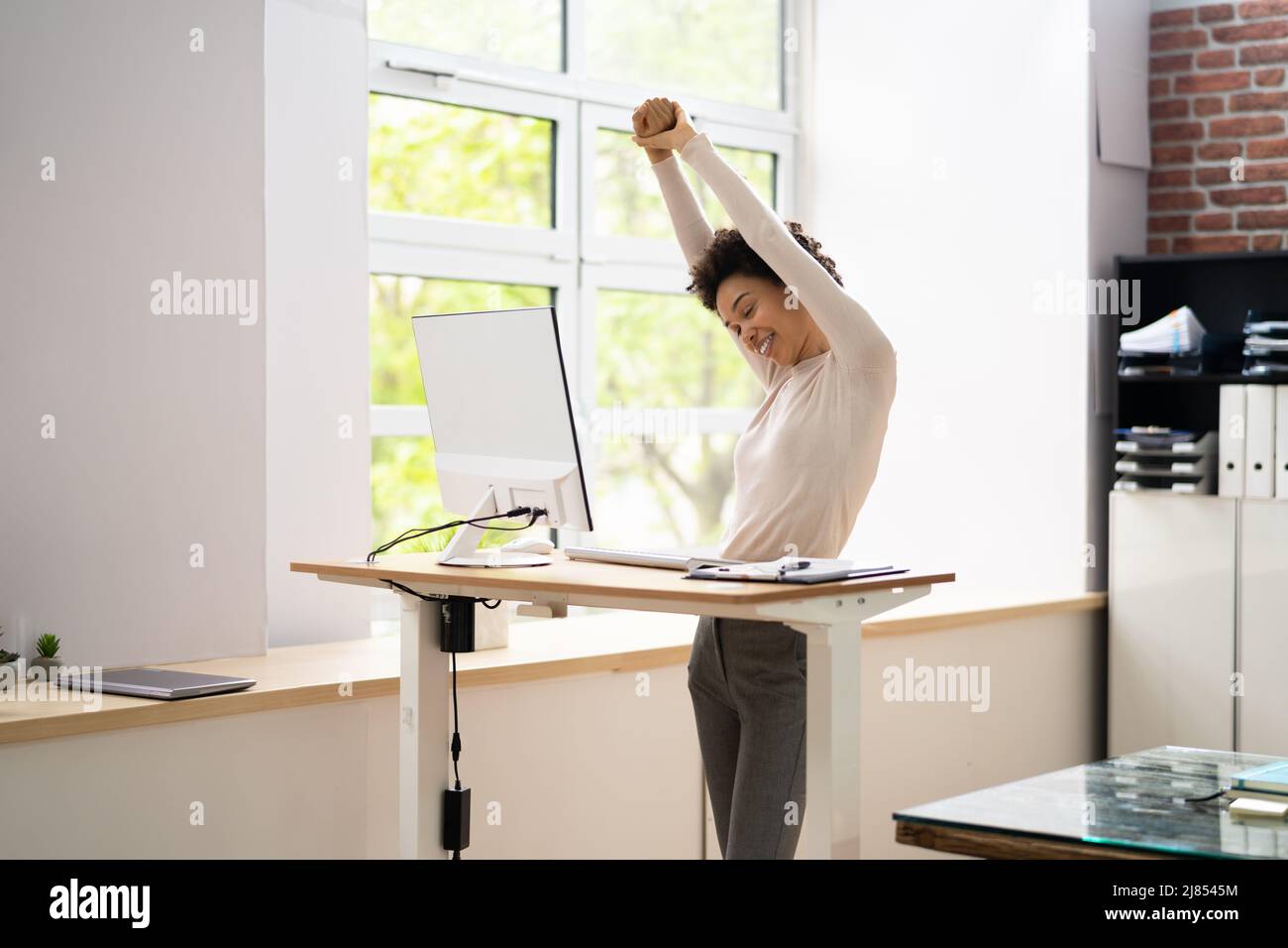 Worker Stretch Exercise At Stand Desk In Office Stock Photo - Alamy