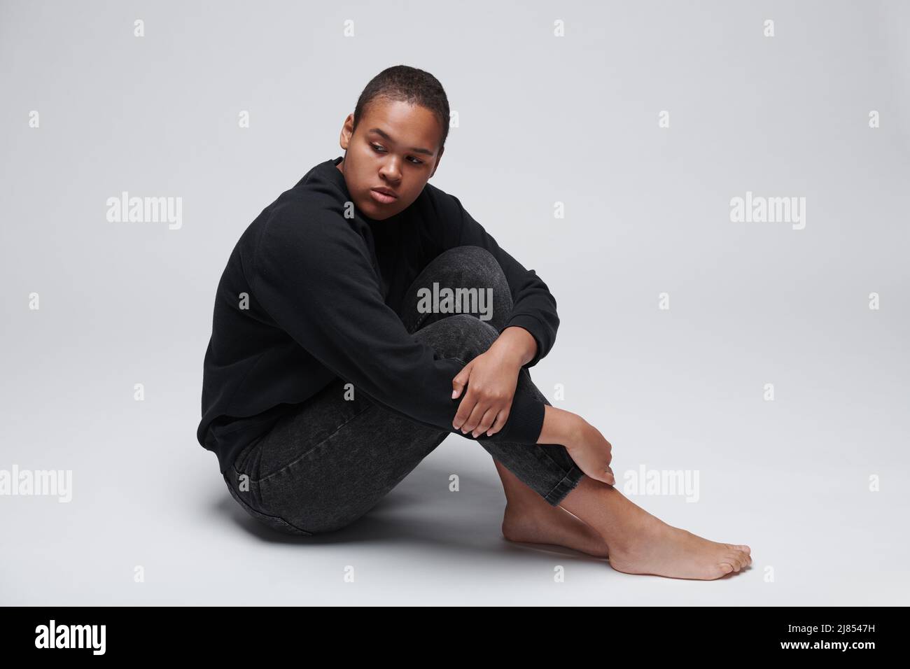 Dejected young Black woman having fear sitting on floor and embracing ...