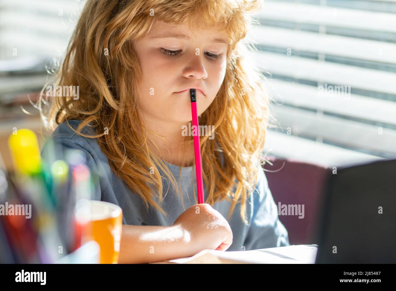 Tired schoolboy while doing homework. Cute pupils writing at desk in ...