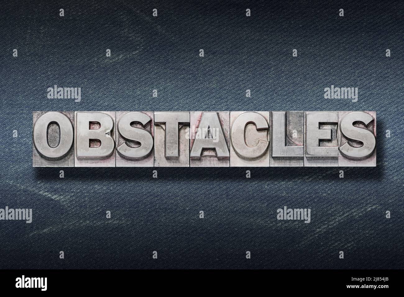 obstacles word made from metallic letterpress on dark jeans background ...