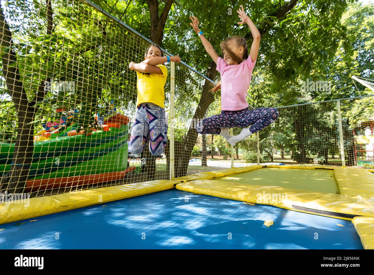 Little pretty girls having fun outdoor. Jumping on trampoline in ...