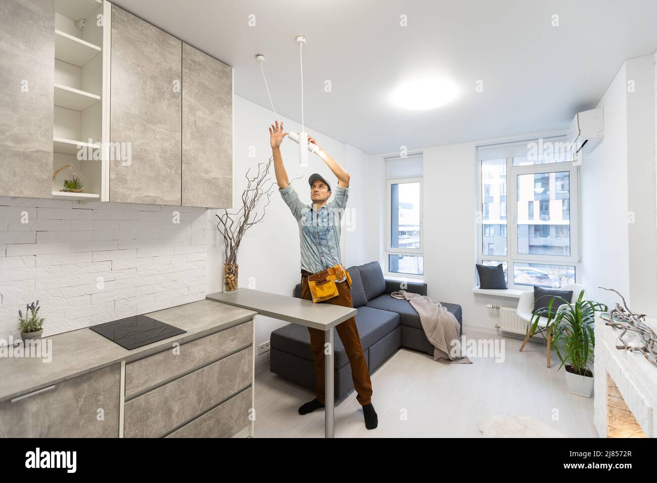 Repairman fixing ceiling lamp in cafe kitchen Stock Photo - Alamy