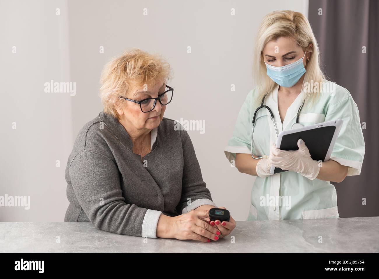 Female caregiver with fingertip pulse oximeter,attached on finger of ...