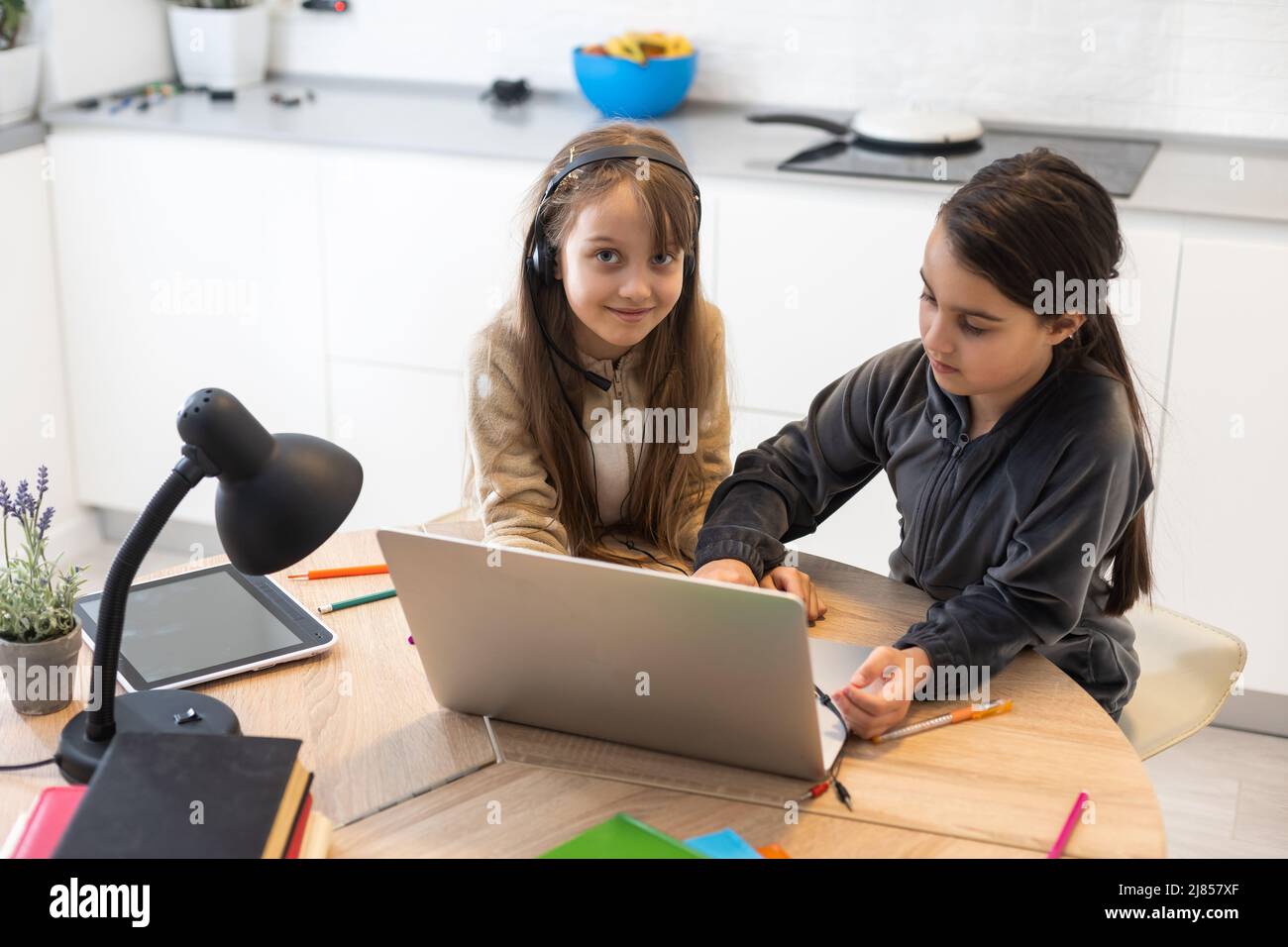 Two child girl students study online with teacher by video call ...