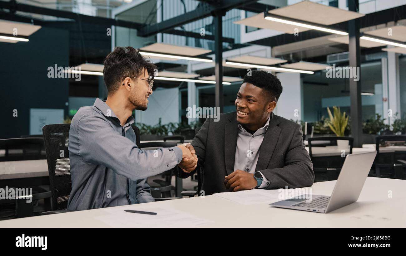 Two diverse men arabian african colleagues co-workers cooperate discuss ...