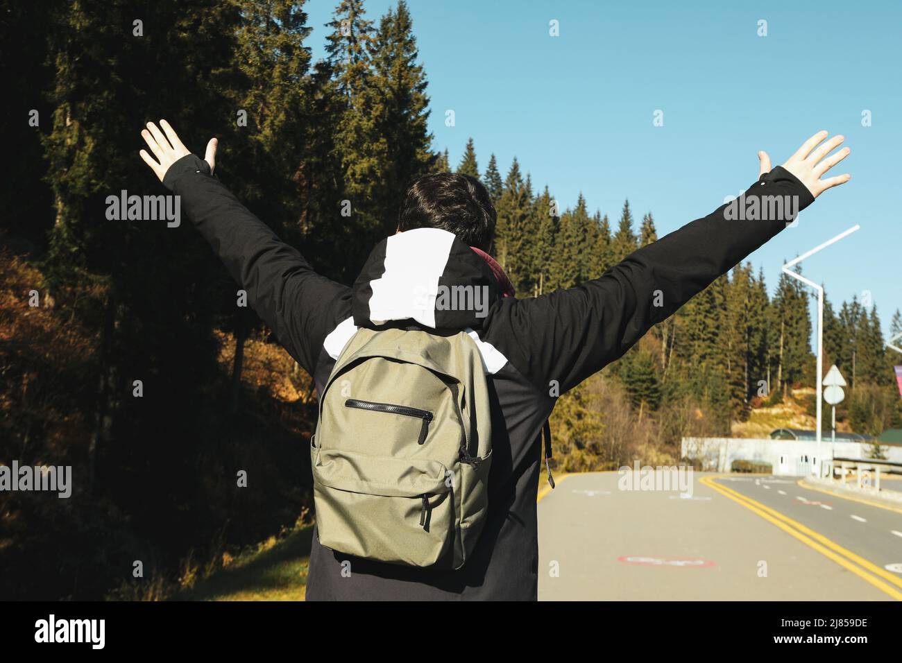 Man with backpack standing with raised hands in road Stock Photo - Alamy