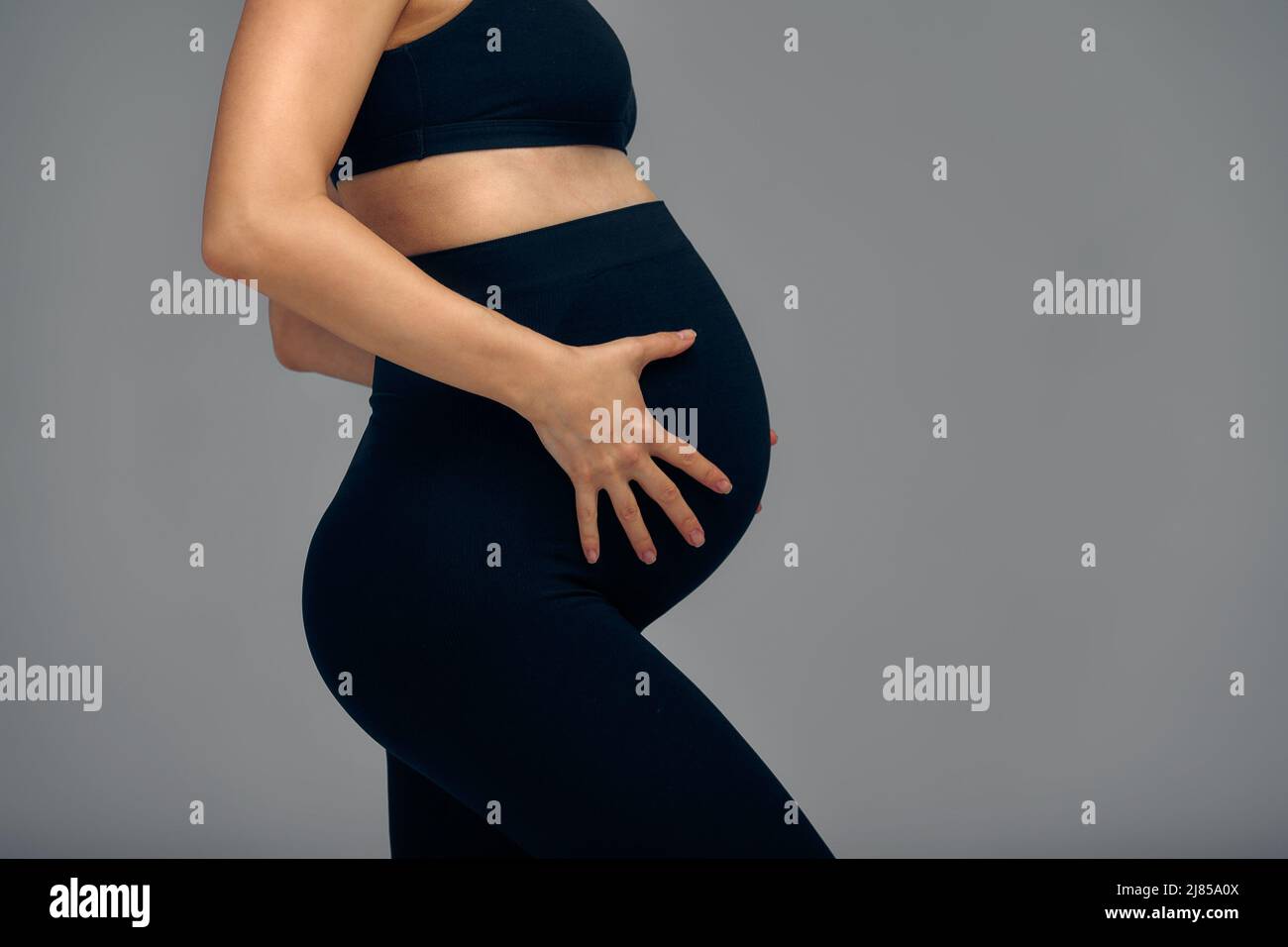 Cute pregnant belly isolated on gray. Side view of young pregnant woman ...