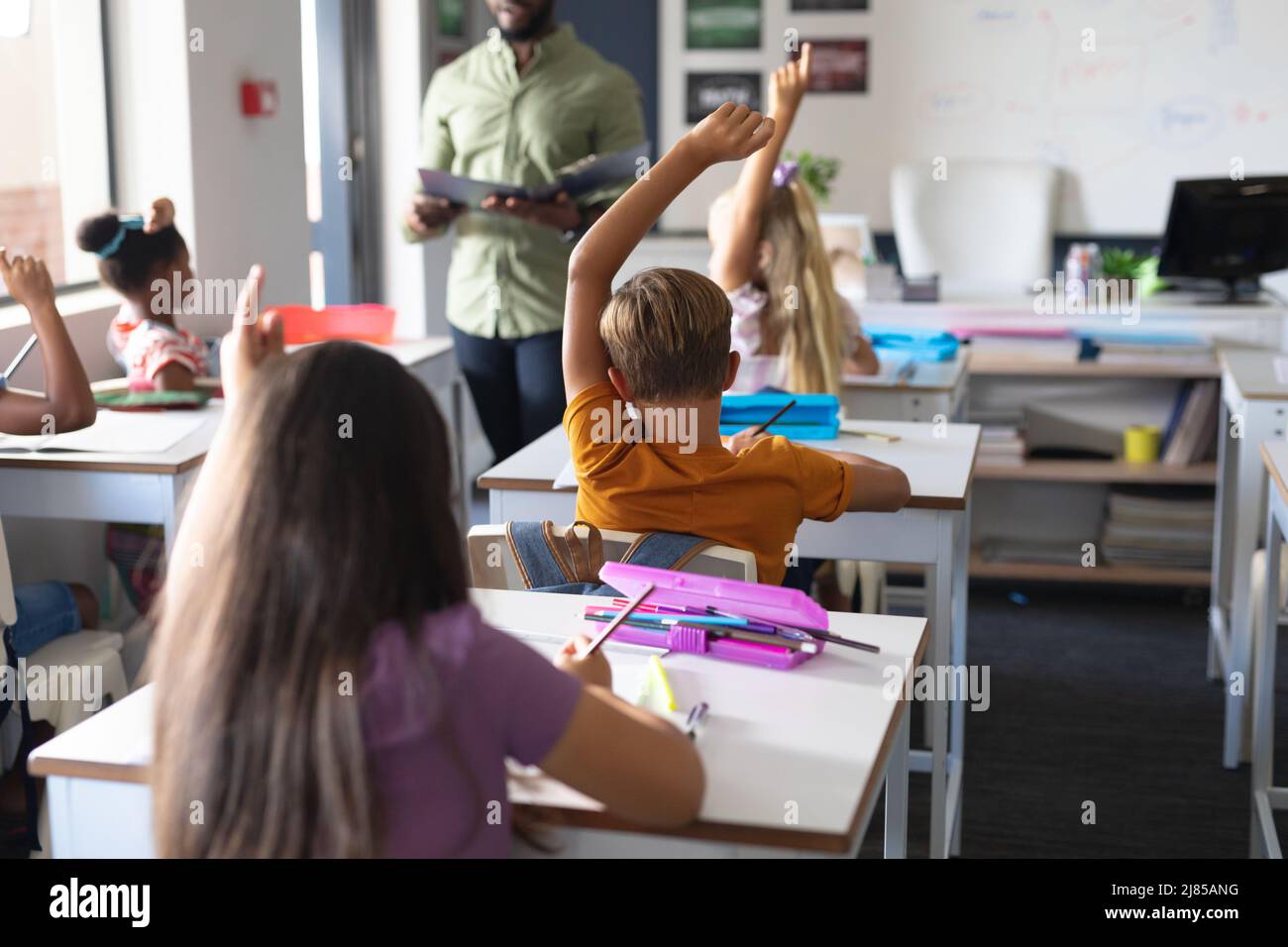 Multiracial students raising hand while african american young male ...