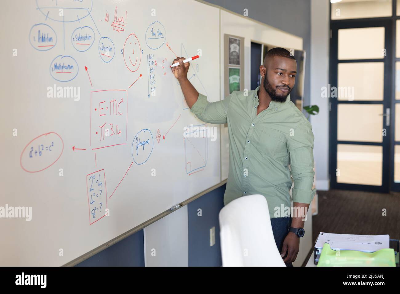 African american young male teacher looking away while writing on ...