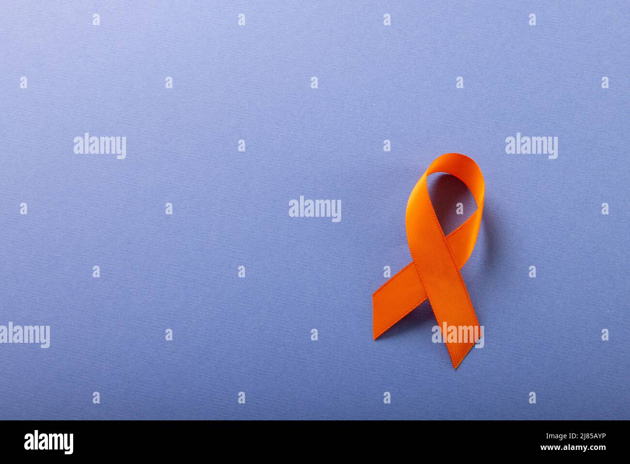 Overhead view of orange leukemia awareness ribbon isolated over blue ...