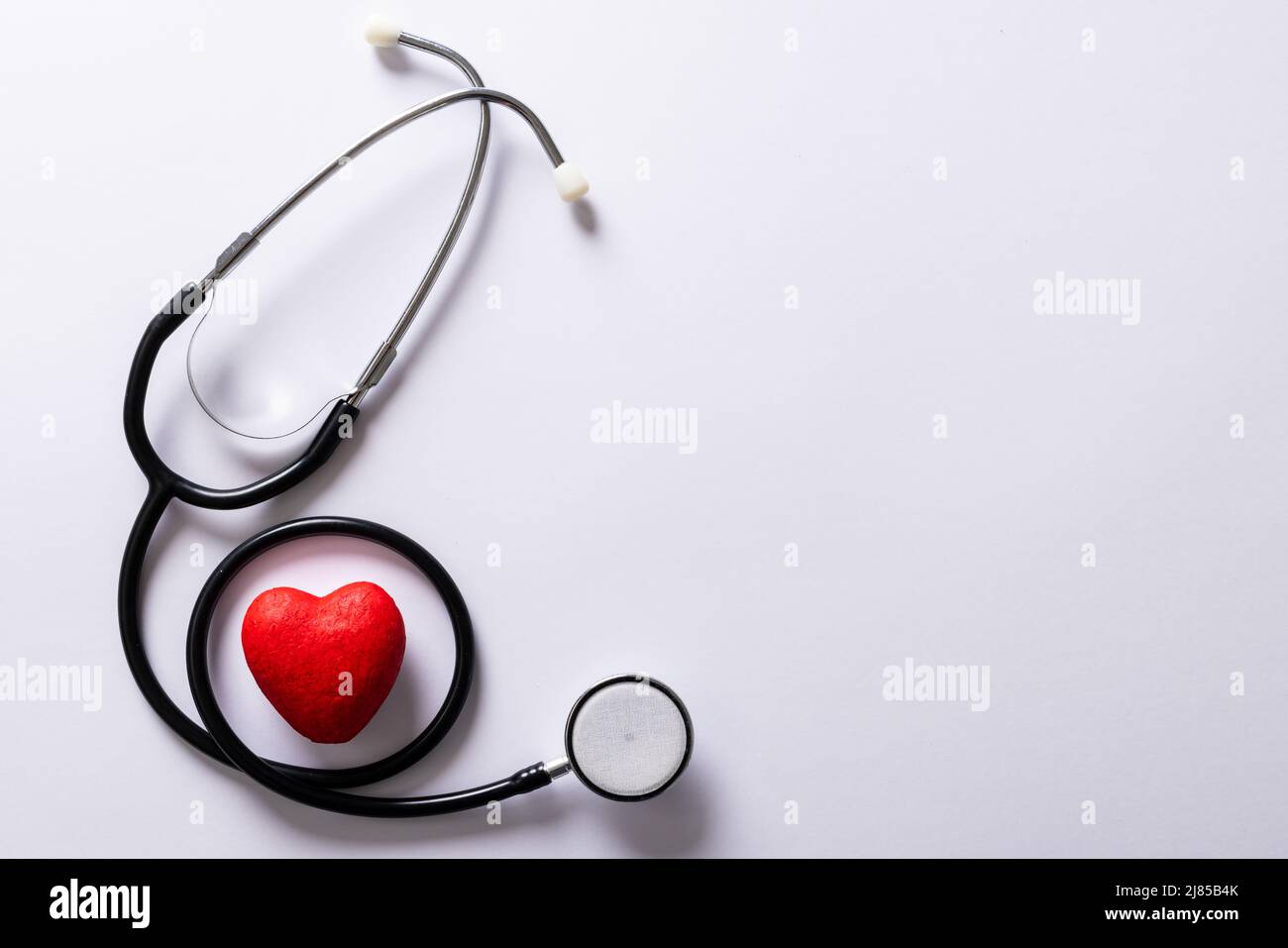 Overhead view of red heart shape with stethoscope against white ...