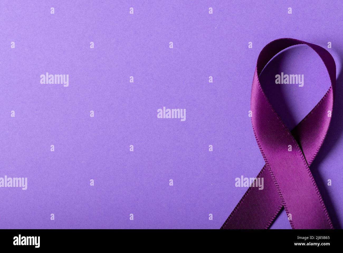 Directly above shot of purple awareness ribbon isolated against purple ...