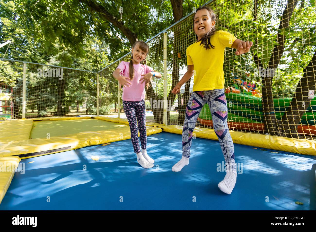 two young active girls doing exercises for squatting with trampoline ...