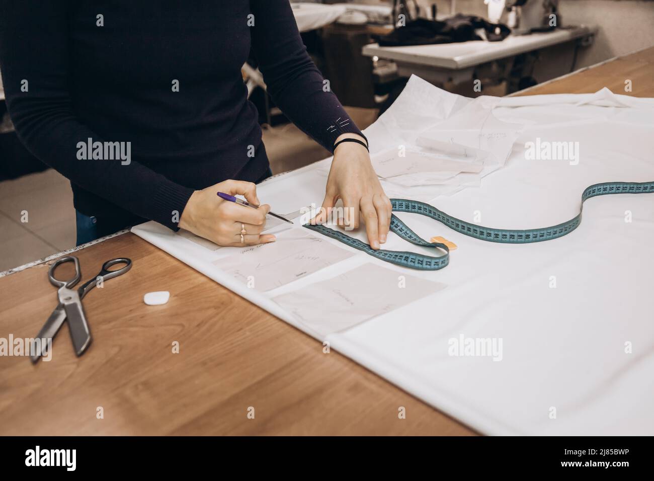 Tailor sews clothes. A woman dressmaker makes patterns in her atelier ...