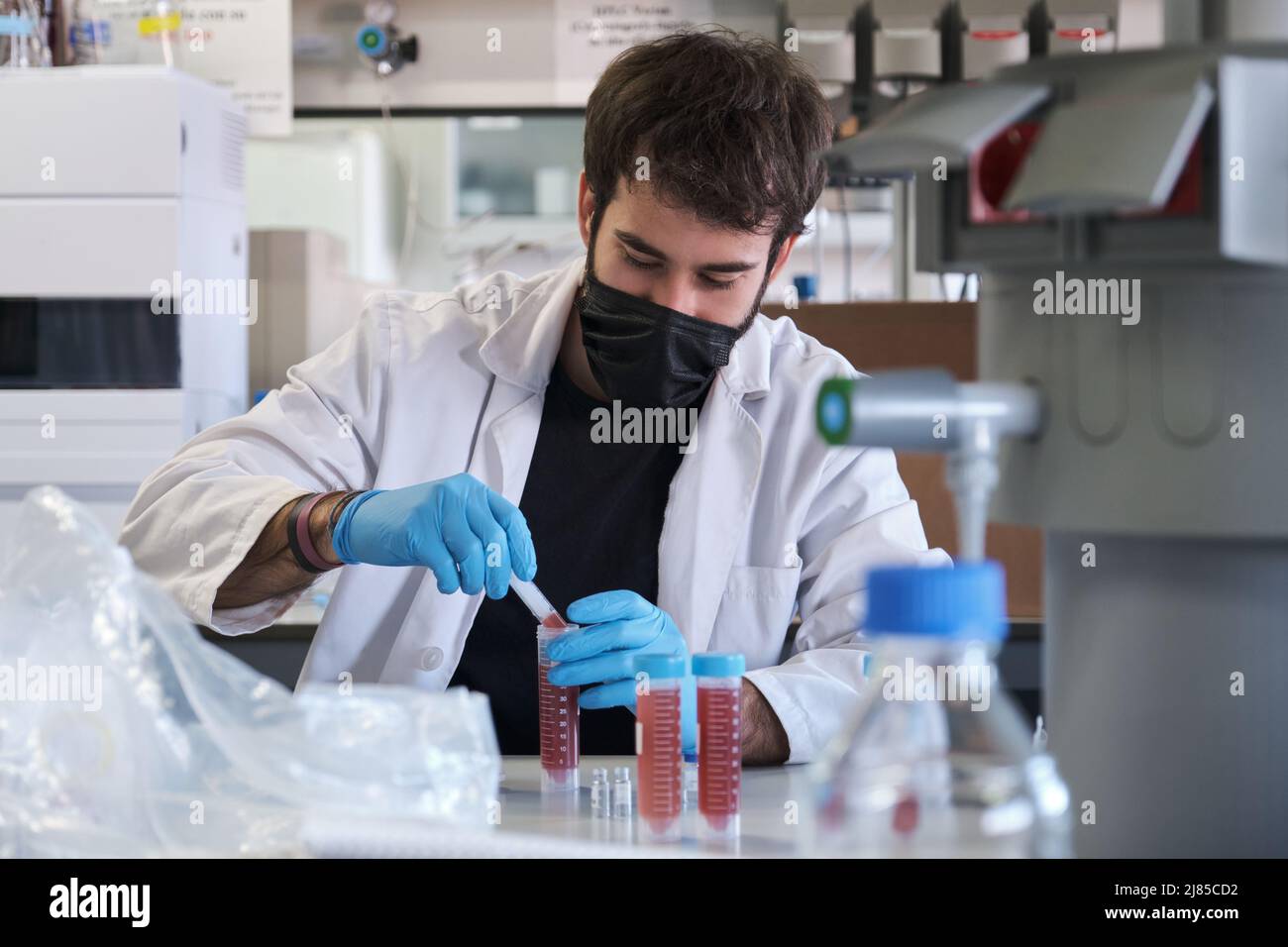 Young researcher wearing protective face mask working in a real ...
